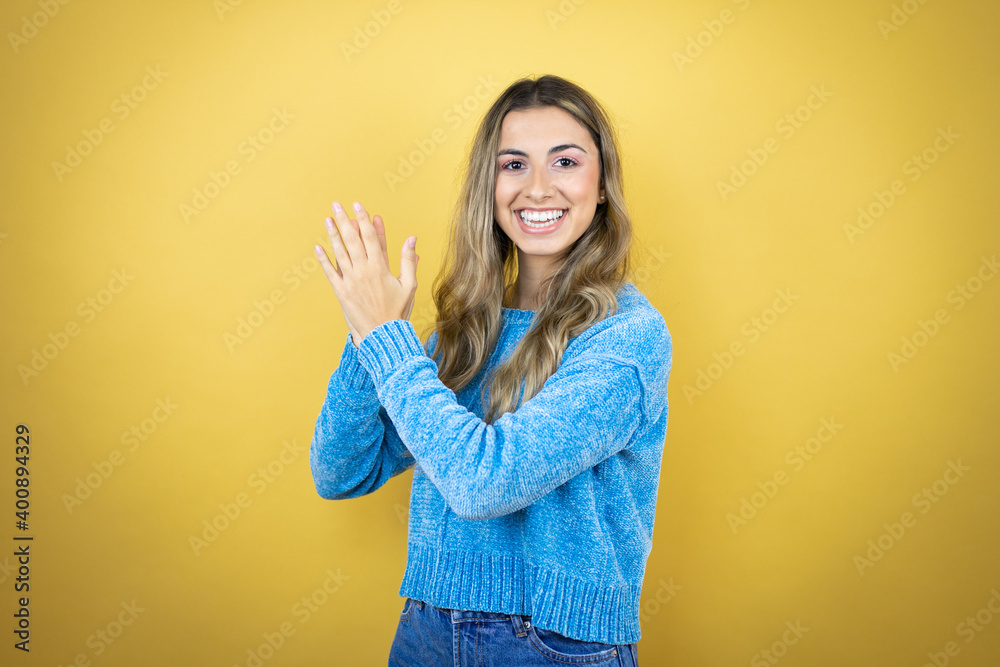 Pretty blonde woman with long hair standing over yellow background ...