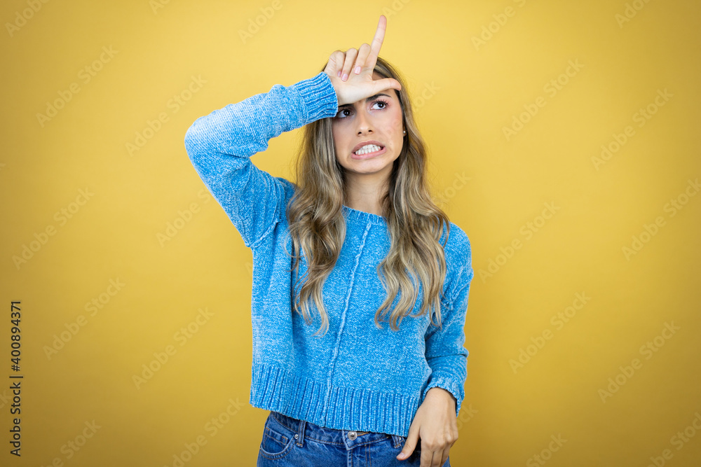 Pretty blonde woman with long hair standing over yellow background ...