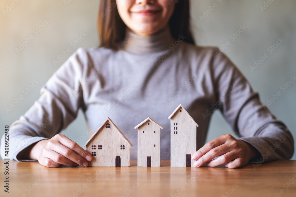 Closeup image of a woman holding wooden house models on the table Stock ...