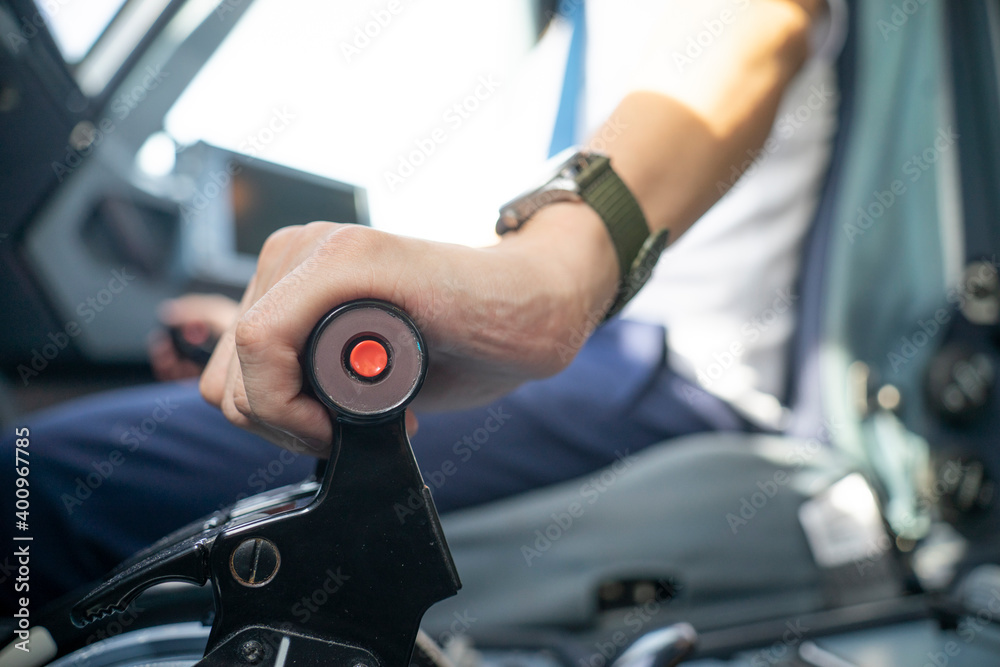 Cropped hands of pilot flying a commercial airplane, cockpit view close ...
