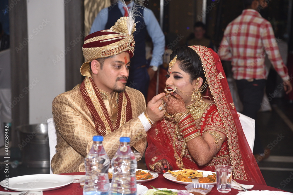 Bride groom having food during wedding ceremony. Both are wearing ...