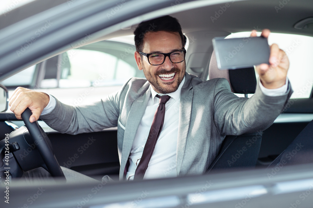 Visiting car dealership. Handsome man is doing selfie with his new car ...