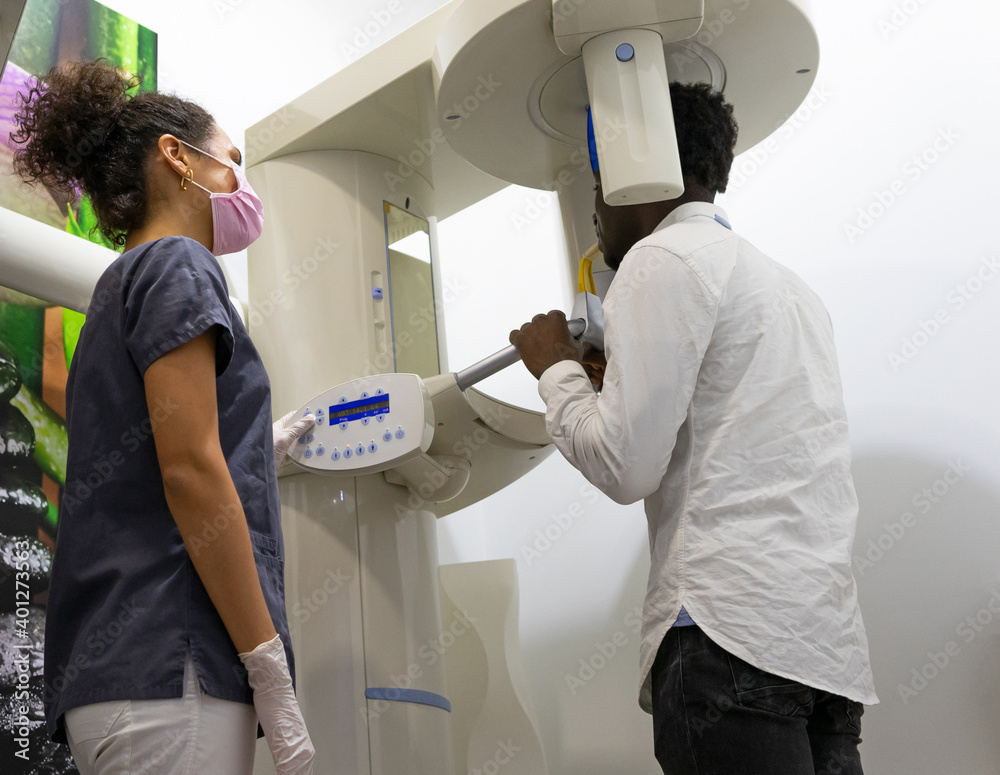 From below side view of dentist taking X ray of teeth of black male ...