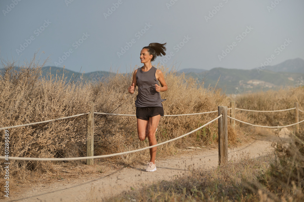 Full body of tanned female running in dry field and enjoying sport near ...