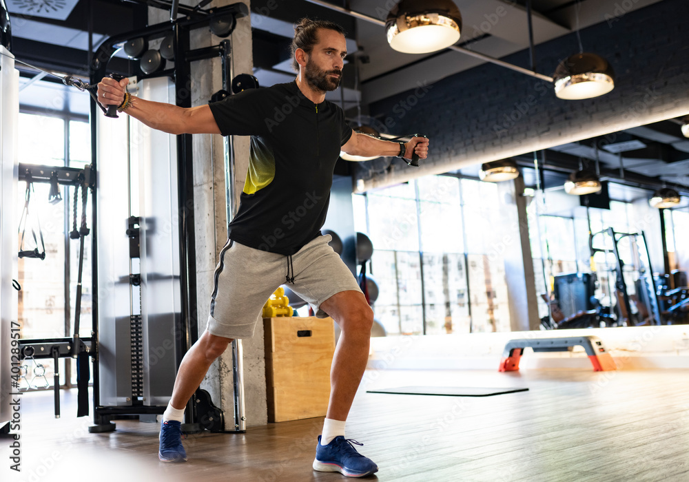 Side view of strong male lifting heavy weights on exercise machine ...