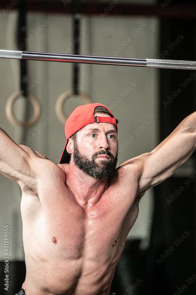 Muscular focused shirtless male athlete doing clean and jerk exercise ...