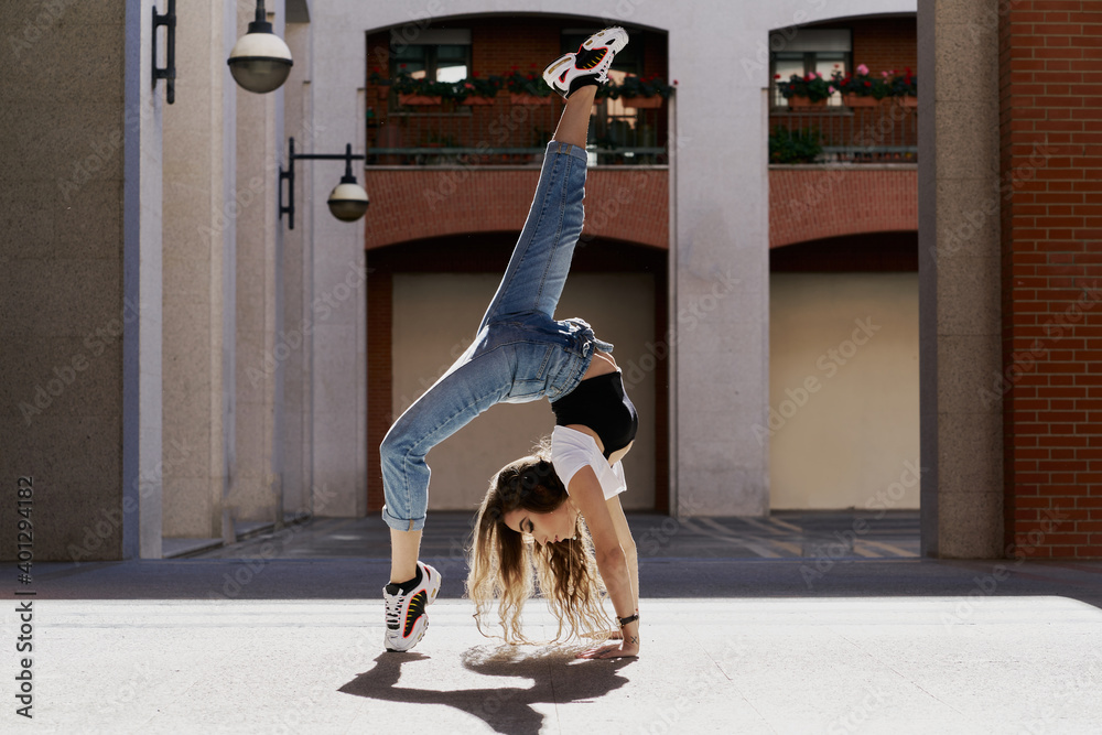 Full body side view of young female dancer in hipster outfit performing ...