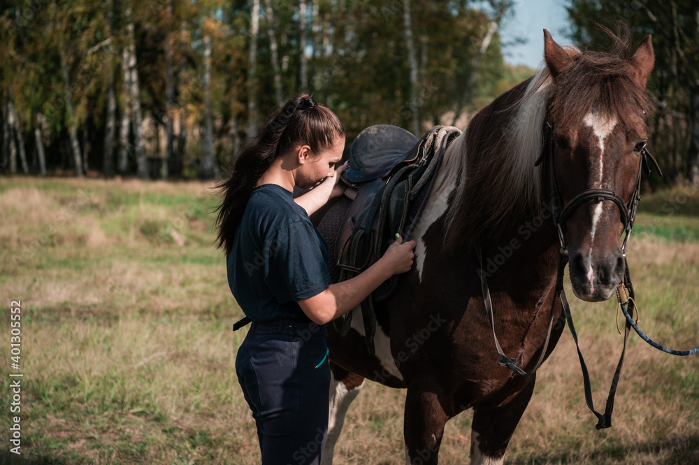 The process of saddling a horse is demonstrated by a young instructor a ...