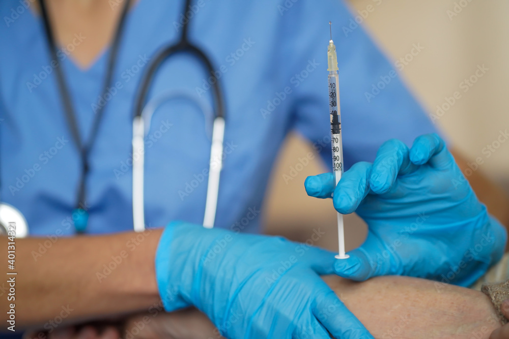The nurse makes an injection with the vaccine to the patient at home. A ...