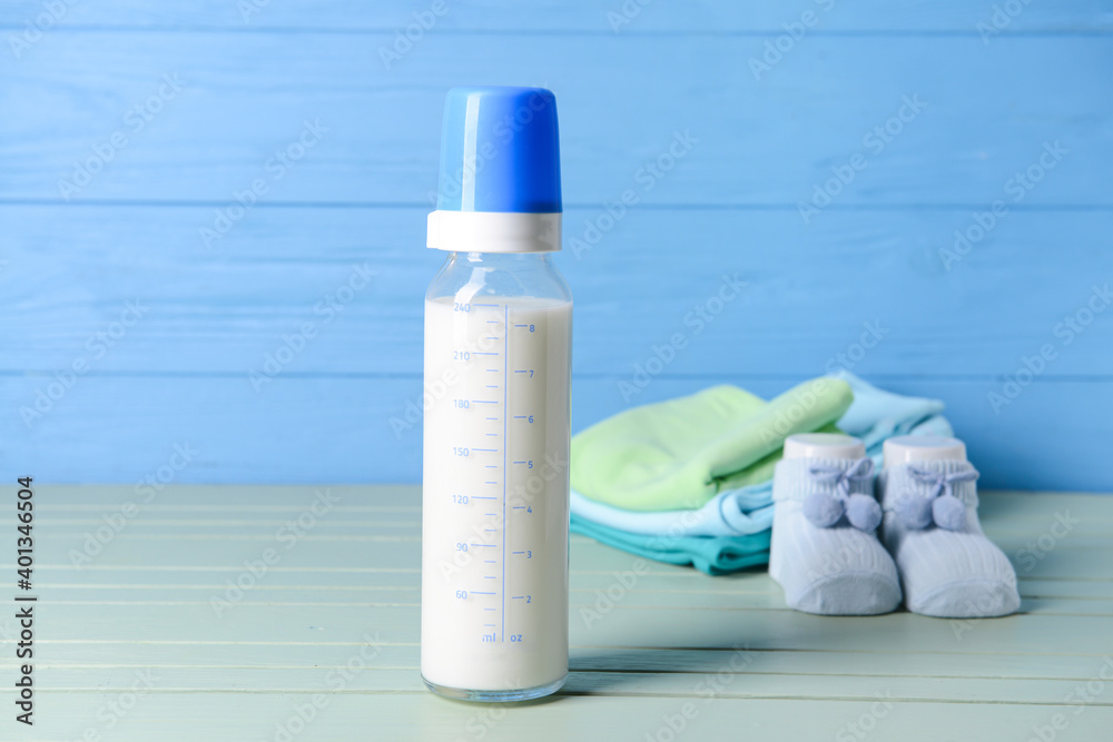 Bottle of milk for baby with clothes on color wooden background Stock ...