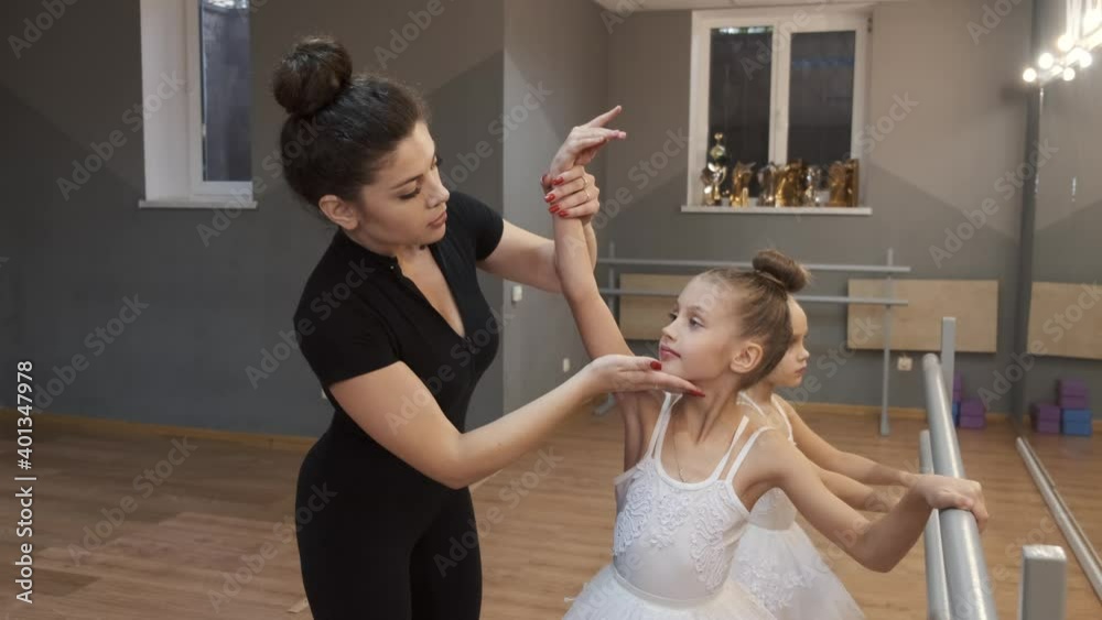 Ballet teacher teaching young dancers. Female ballet teacher helping ...