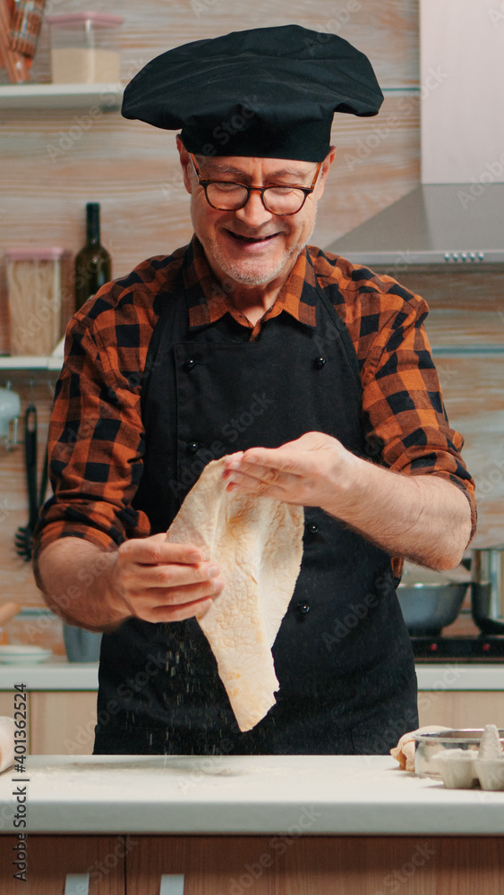 Fotka „Chef throwing up dough for pizza at home in modern kitchen ...