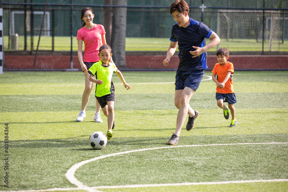 Happy young family playing football on soccer field Stock Photo | Adobe ...
