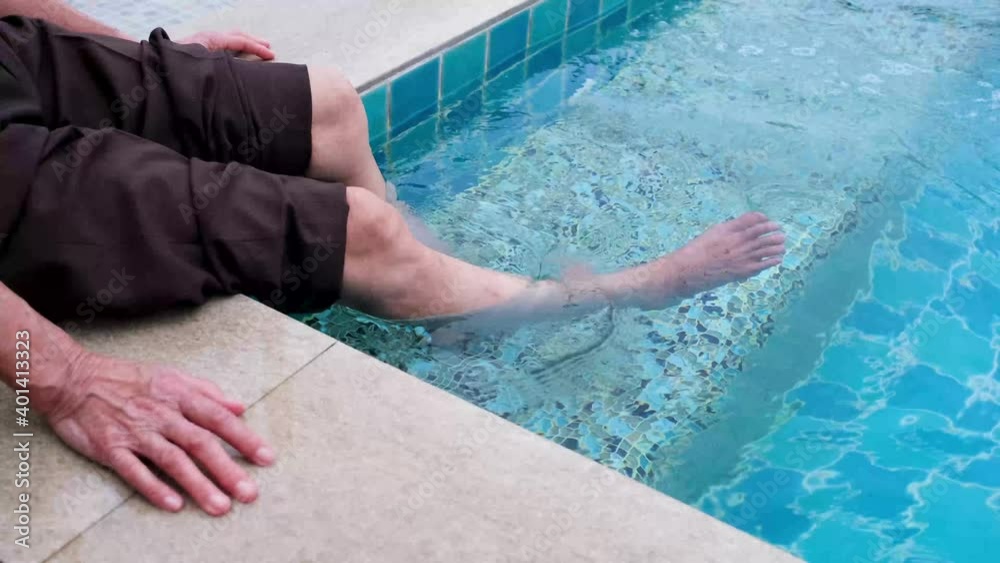 An old Asian woman's legs are soaking their feet in the pool and ...
