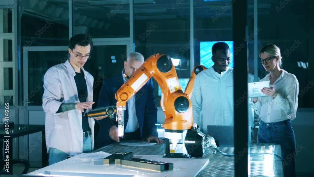 Team of industrial robotics engineers working with robot arm. Engineers ...