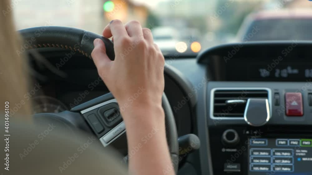 Rear view of female driver behind steering wheel driving a car on a ...