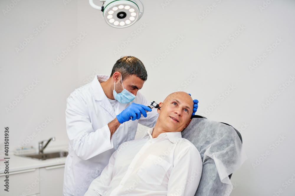 Doctor ENT checking ear with otoscope to man patient at hospital Stock ...