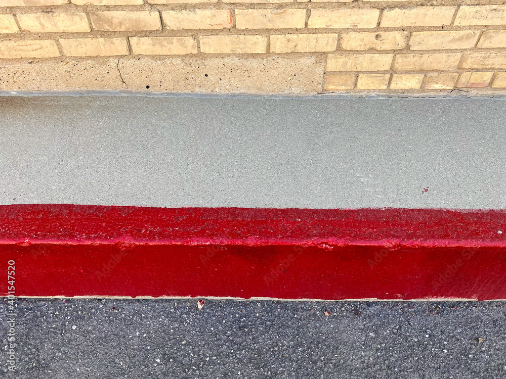 bright red strip painted on sidewalk showing pavement and edge of brick ...