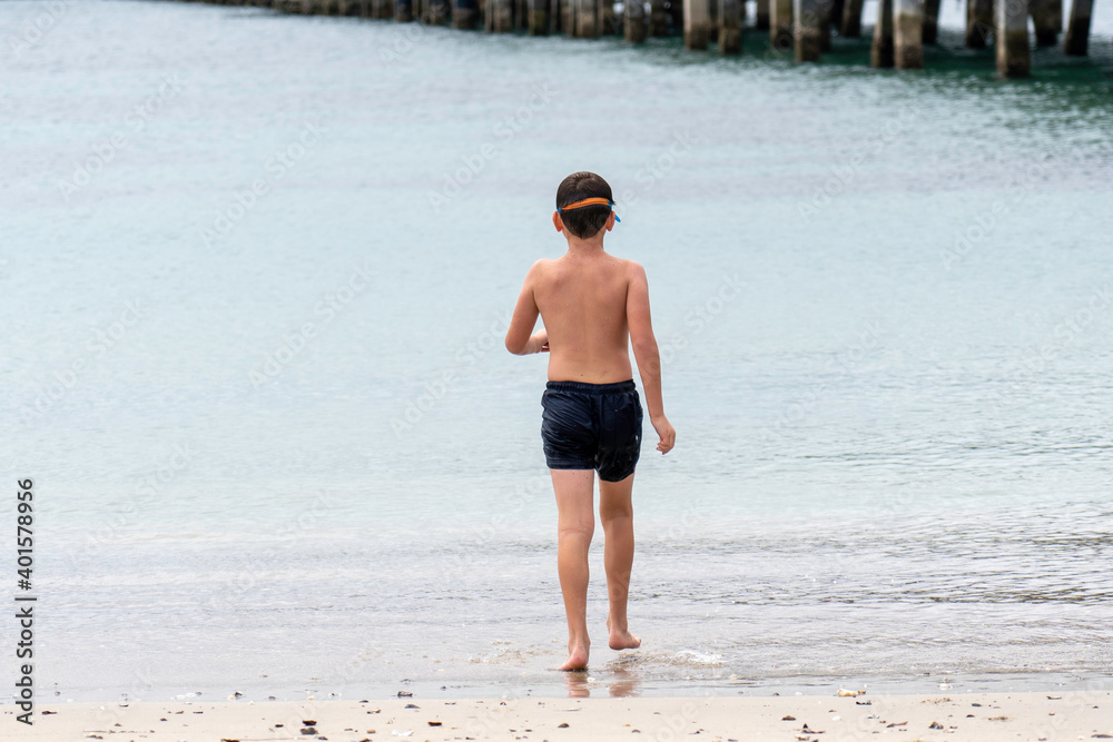 young boy walking into the ocean for a swim, view from behind Stock ...