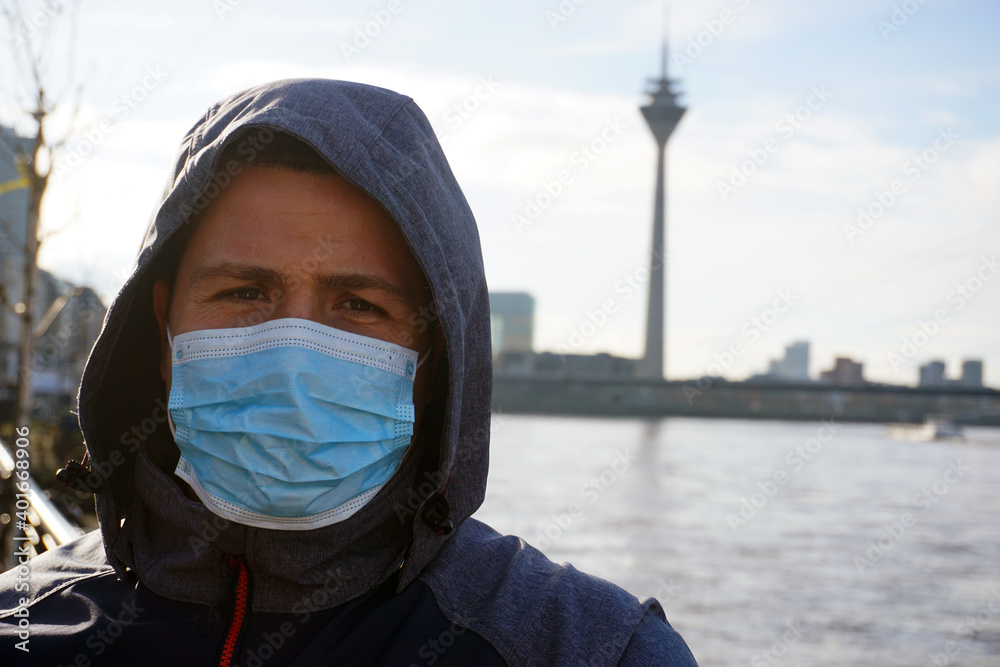 Portrait of a man on a city street. he has put a disposable mask on his ...