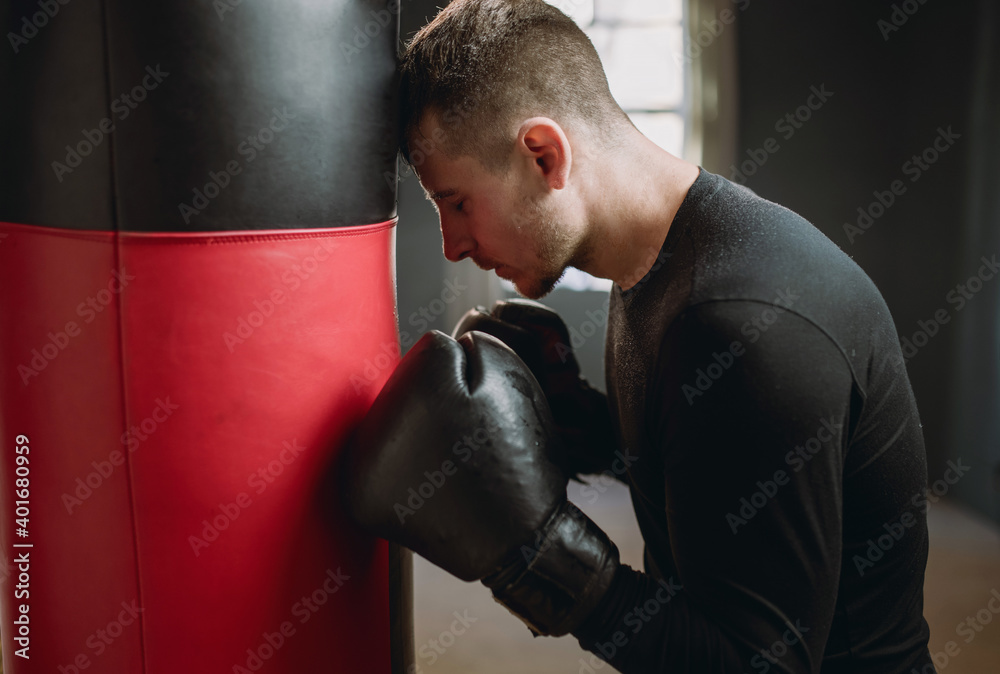 Tired boxer after training. A boxer stands by a punching bag. Workout ...