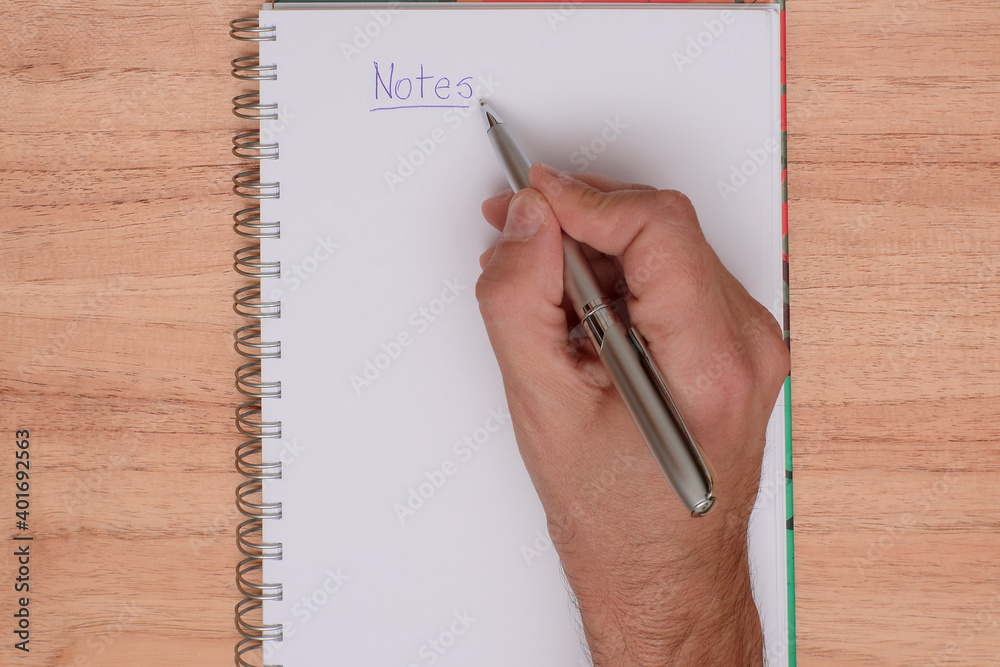Mano anotando en cuaderno blanco con la palabra notas escrita sobre ...