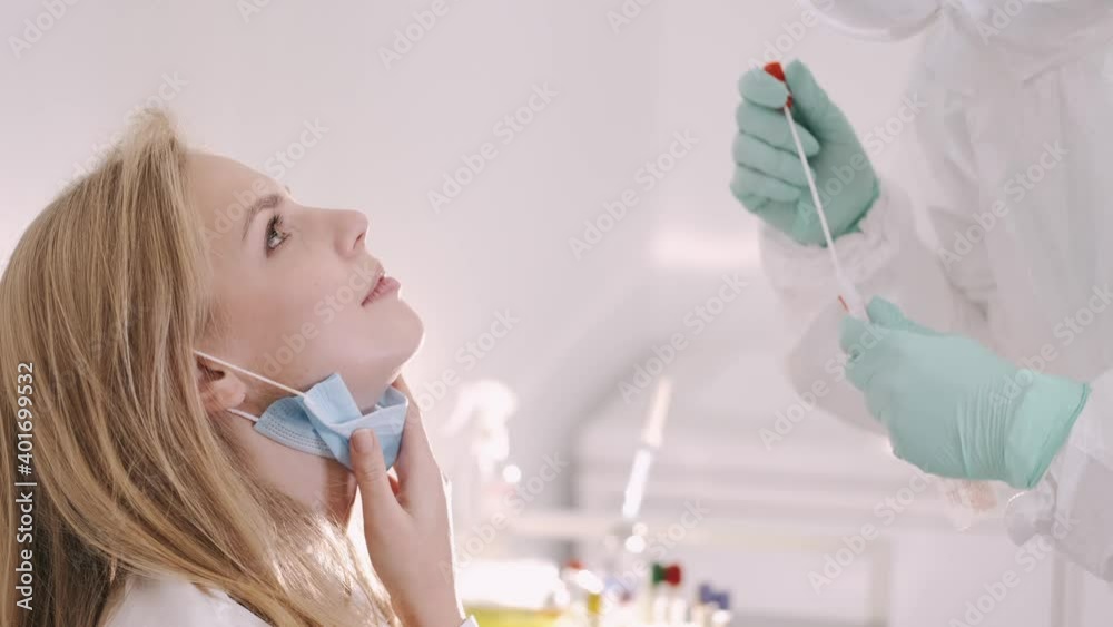 Female doctor in a protective suit taking a nasal swab from a person to ...