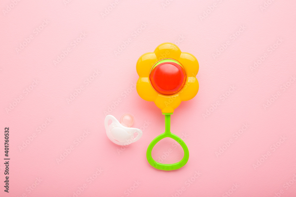 Flower rattle for baby girl and white soother on light pink table ...