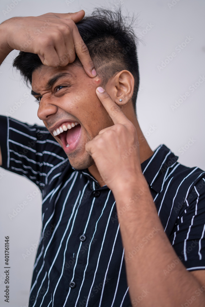 portrait of a young man squeezing pimples standing on a white ...