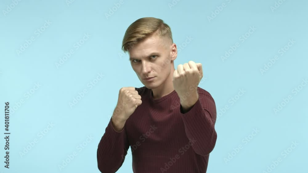 Serious and blond man in casual clothes taunt enemy to attack, beckon ...