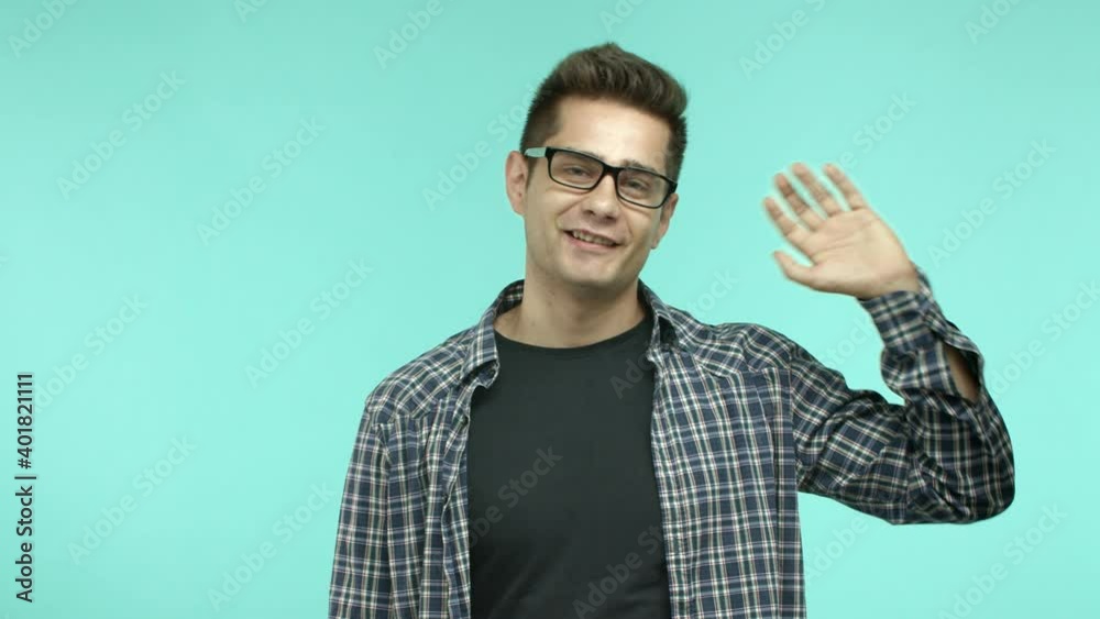 Friendly male model in glasses and casual shirt saying hi, waving hand ...