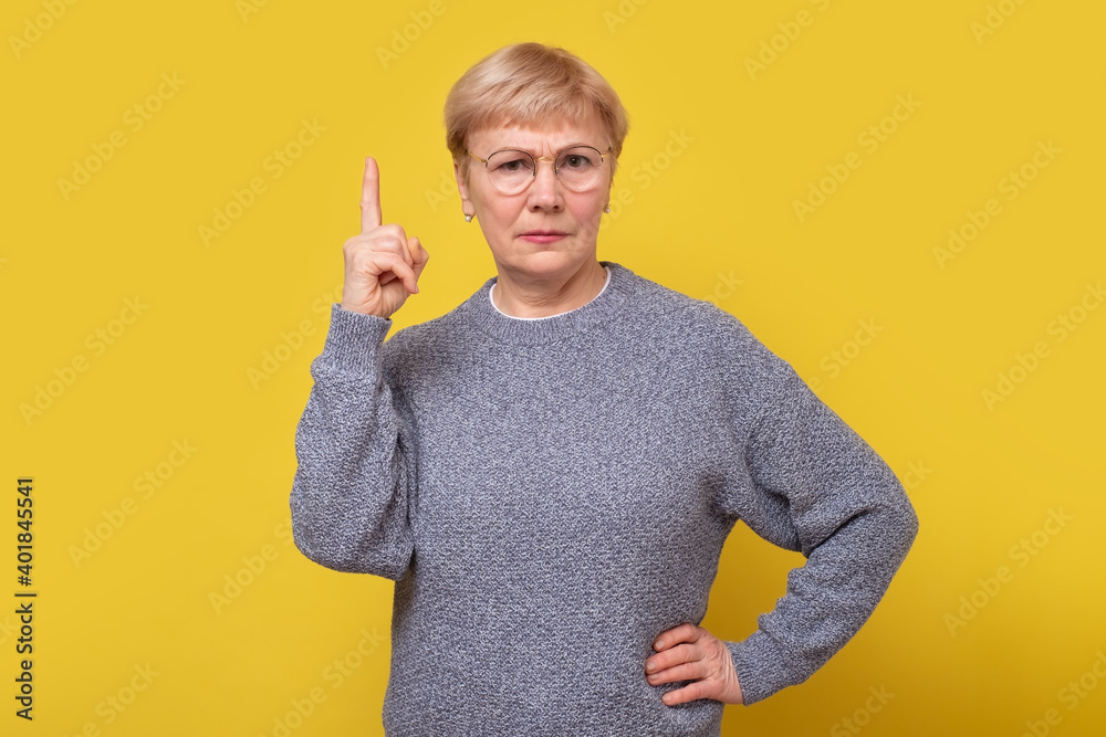 Senior woman pointing up looking angry, indicating direction with ...