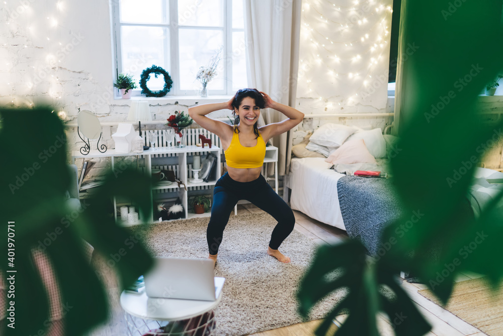 Joyful fit girl with perfect body shape squatting in home interior for ...