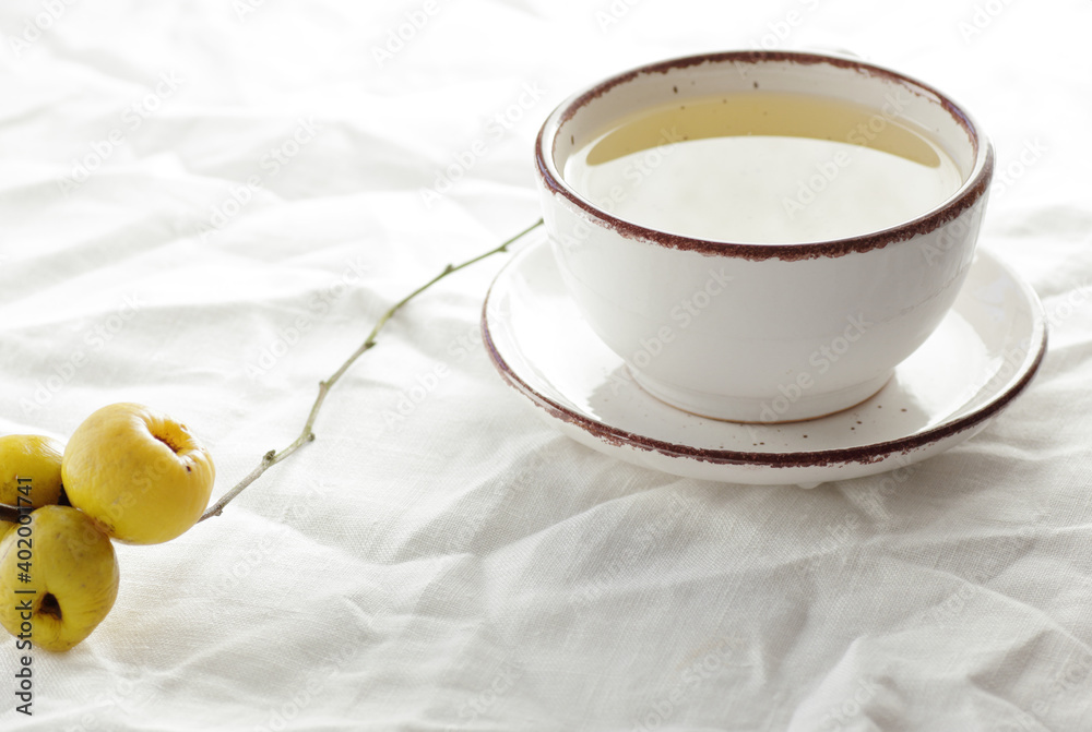 Green tea with japanese quince on white linen textile, minimalist ...