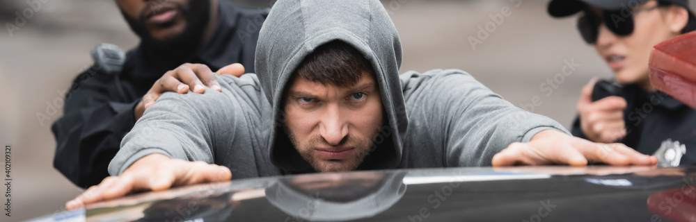 angry offender with outstretched hands leaning on patrol car with ...