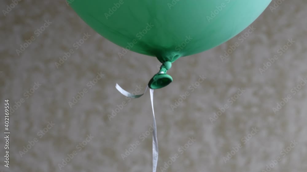 Soft focus to bottom part of green balloon with rubber tail tied with ...
