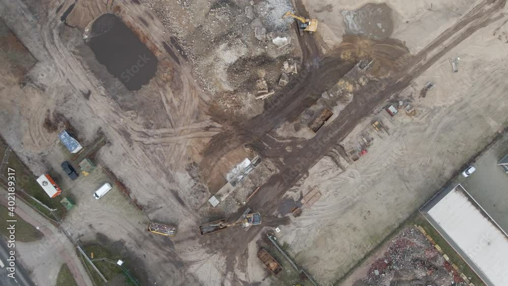 High top down aerial of excavators collecting rubble from demolished ...