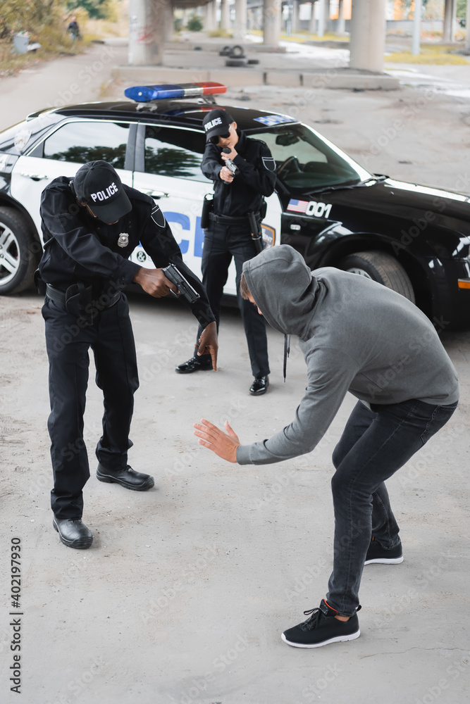 high angle view of multicultural police officers with pistols aiming at ...