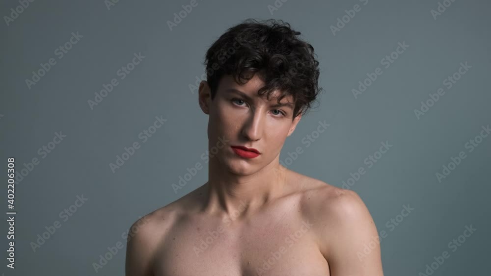 Androgyny. Transgender guy with makeup posing on grey background. Close ...