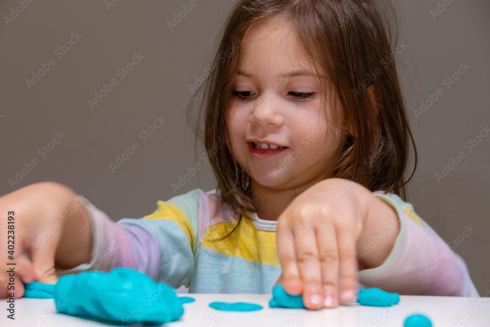 Little girl playing with colorful clay. Cute child girl sits at the ...