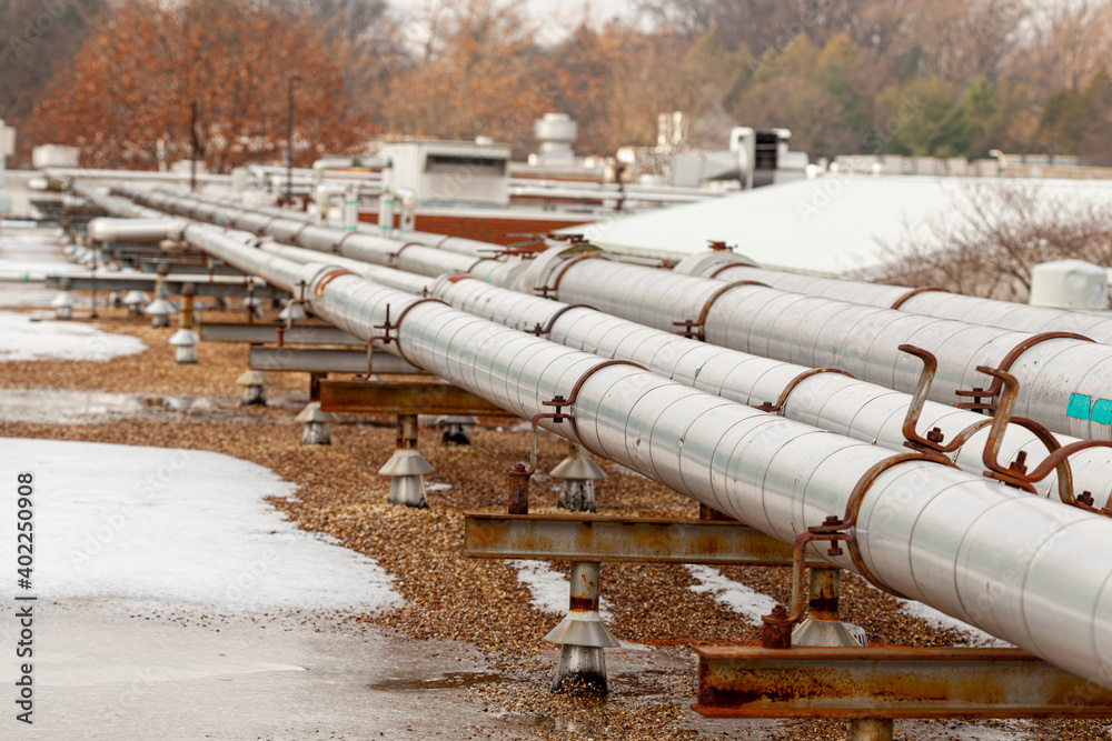 Side view of a pipeline running over snowy terrain near an energy plant ...