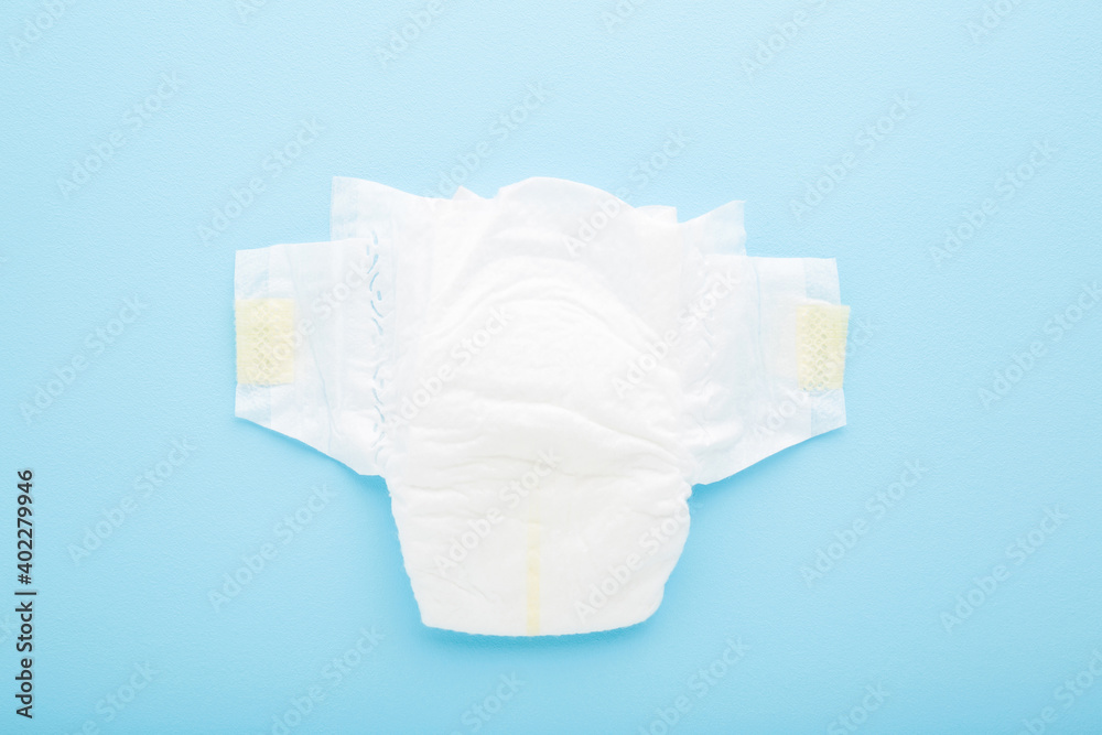 White, soft, new baby diaper on light blue table background. Pastel ...