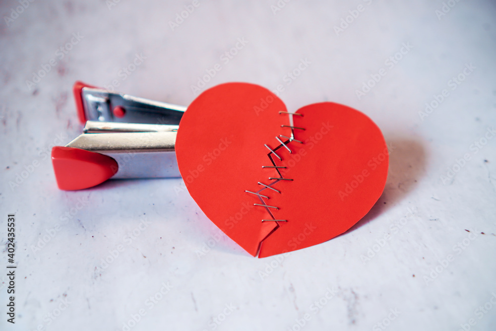 Fixed red Broken heart made from paper with stapler on white concrete ...