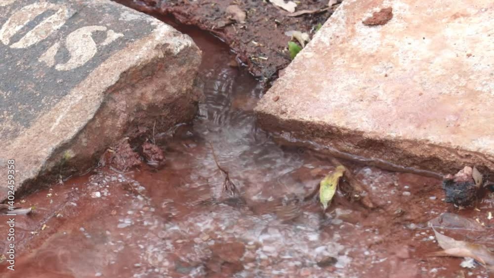 Clean tap water seeping through leaking underground pipe, spilling down ...