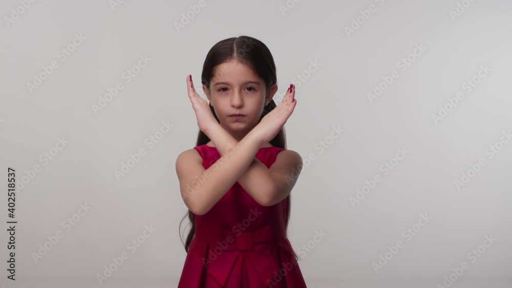 Little girl makes the sign of the cross with her arms.Beautiful little ...