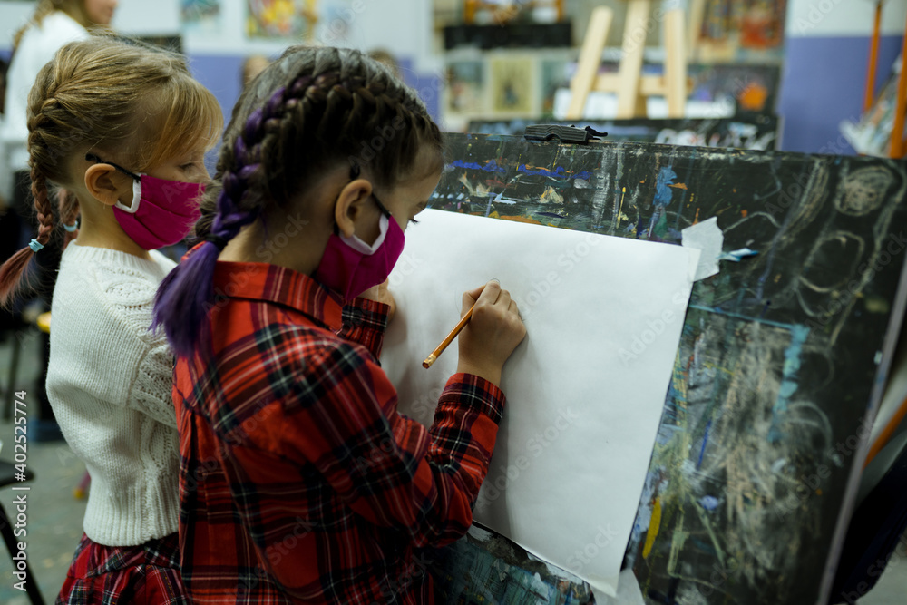 Children in protective equipment at school draw drawings with a pencil ...
