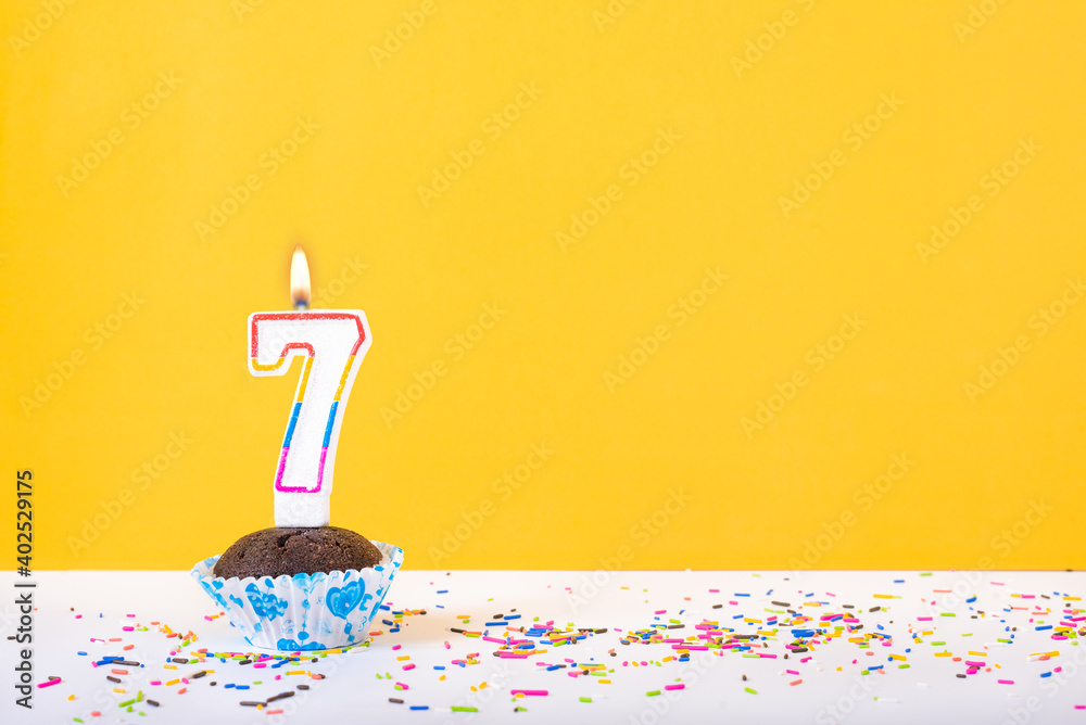 7 number candle on a cup cake with colorful sprinkles and yellow ...