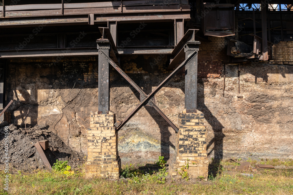 Crumbling brick wall and metal bracing of a derelict industrial ...