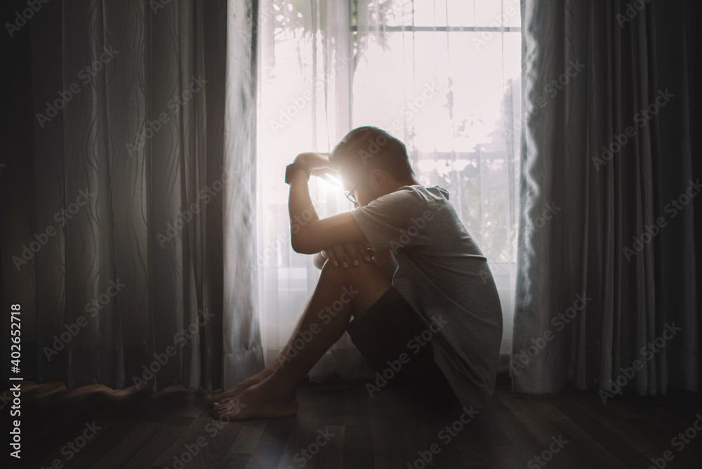 Sad and depressed male sitting on the floor in the living room looking ...