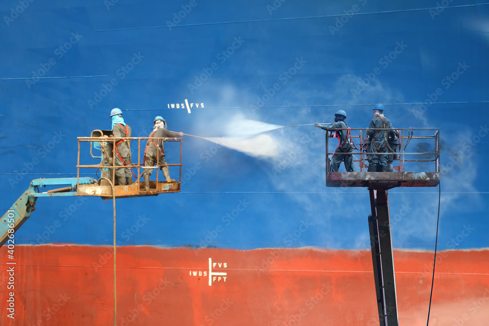 Shipyard worker power washing, cleaning water jet high pressure a ship ...